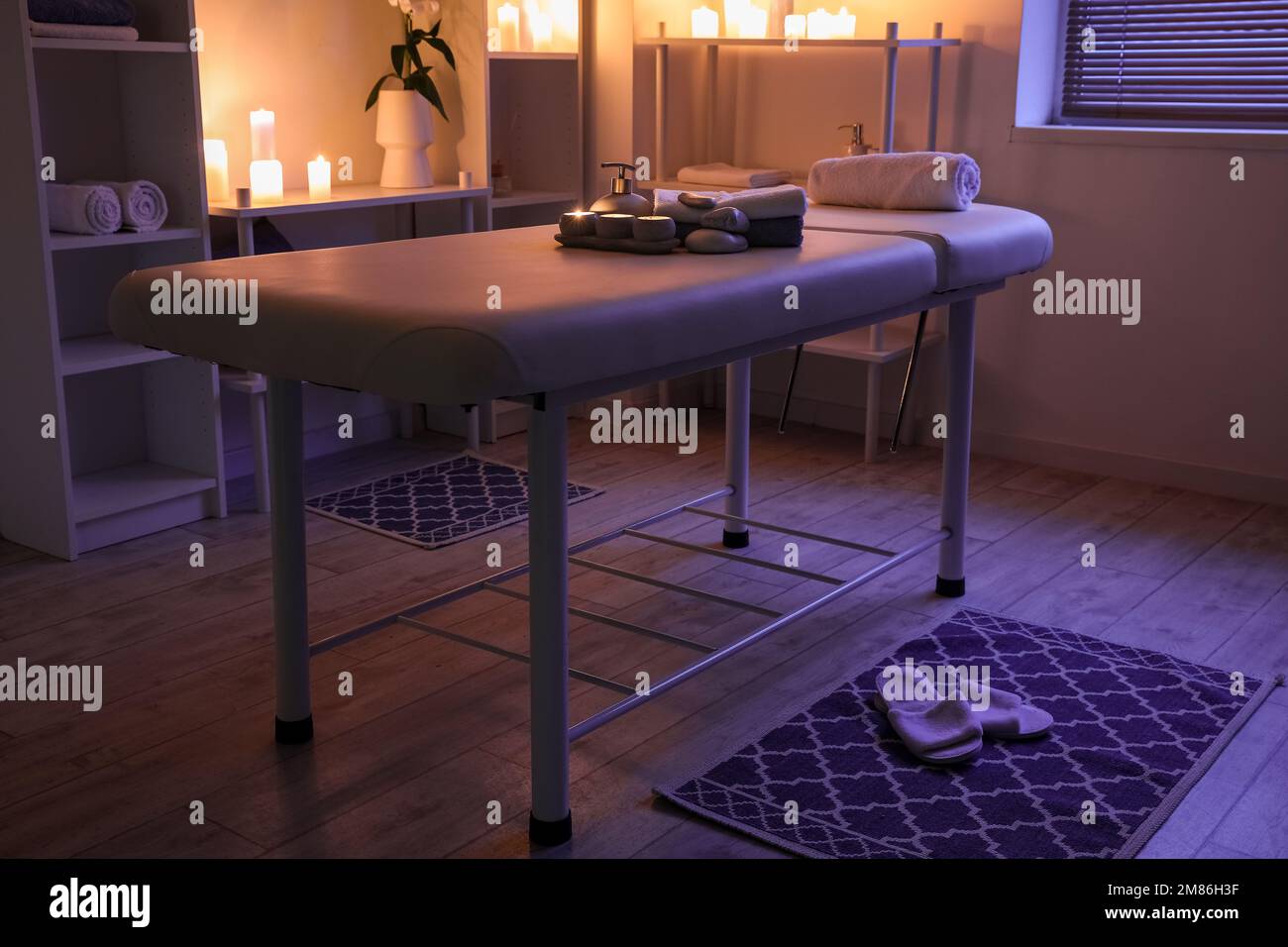 Interior of dark spa salon with couch, shelving units and burning ...