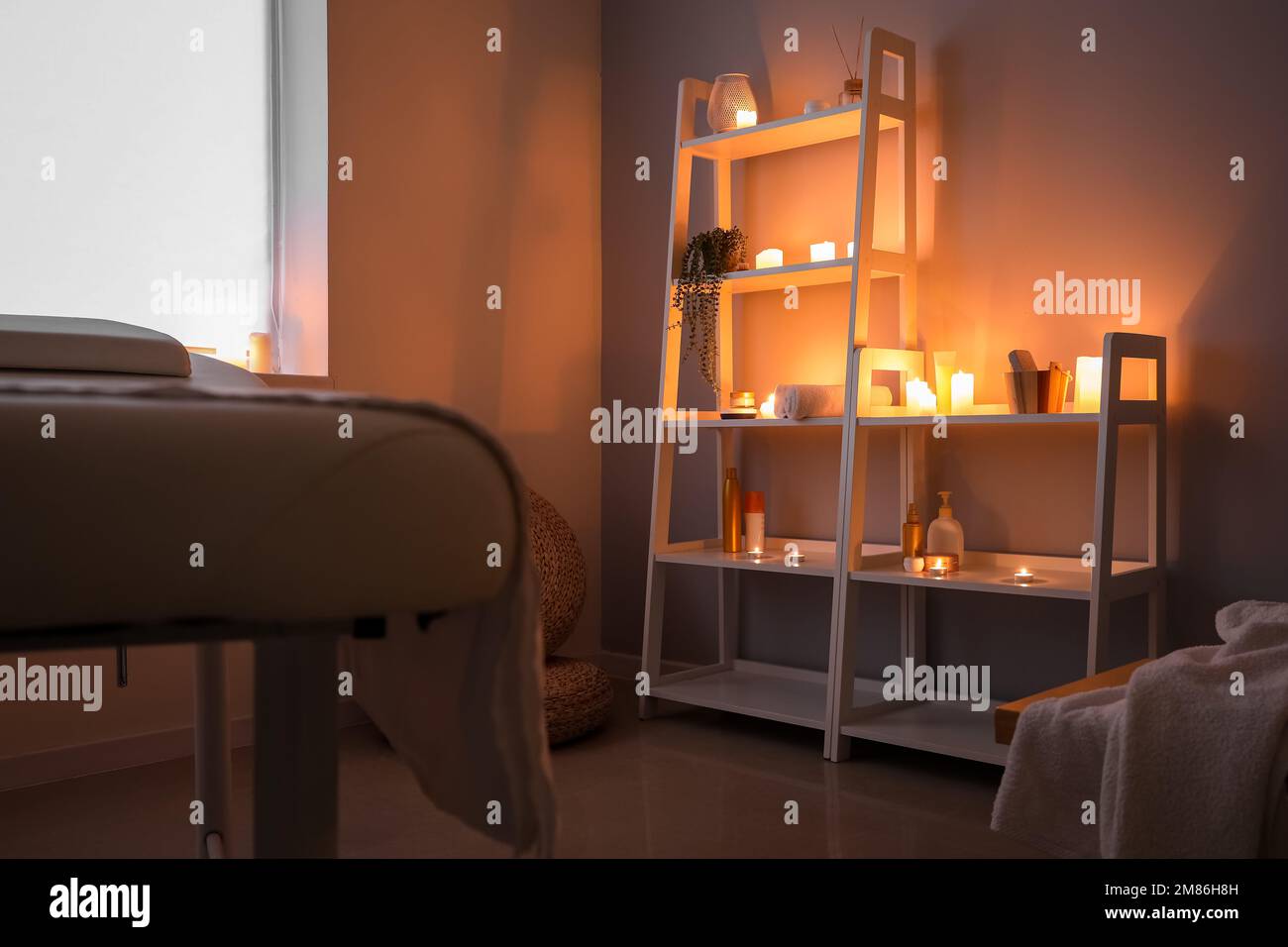 Interior of dark spa salon with couch, shelving units and burning ...