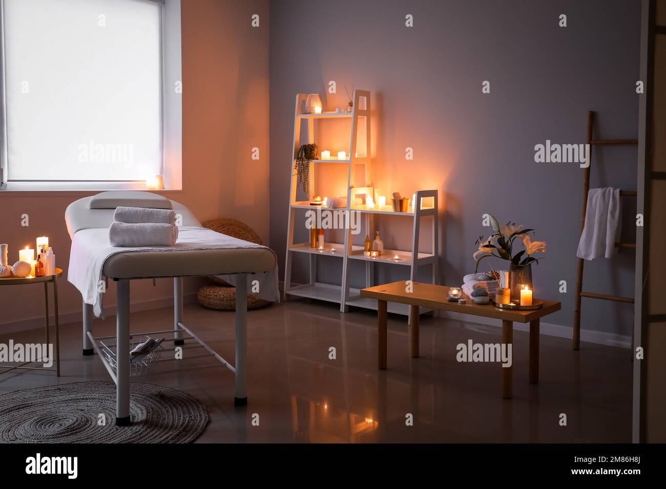 Interior of dark spa salon with couch, shelving units and burning ...