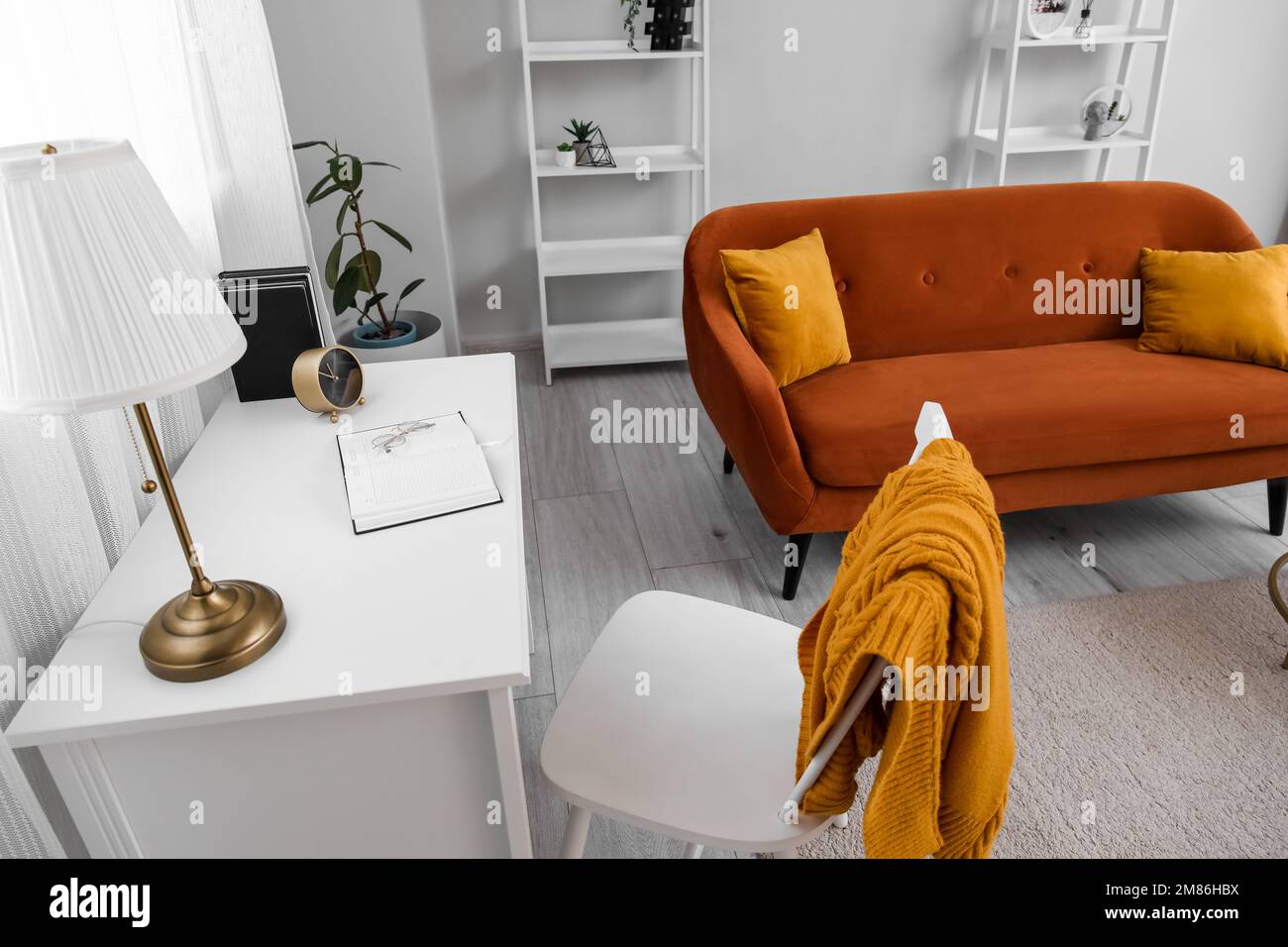 Interior of light living room with brown sofa and table near window ...