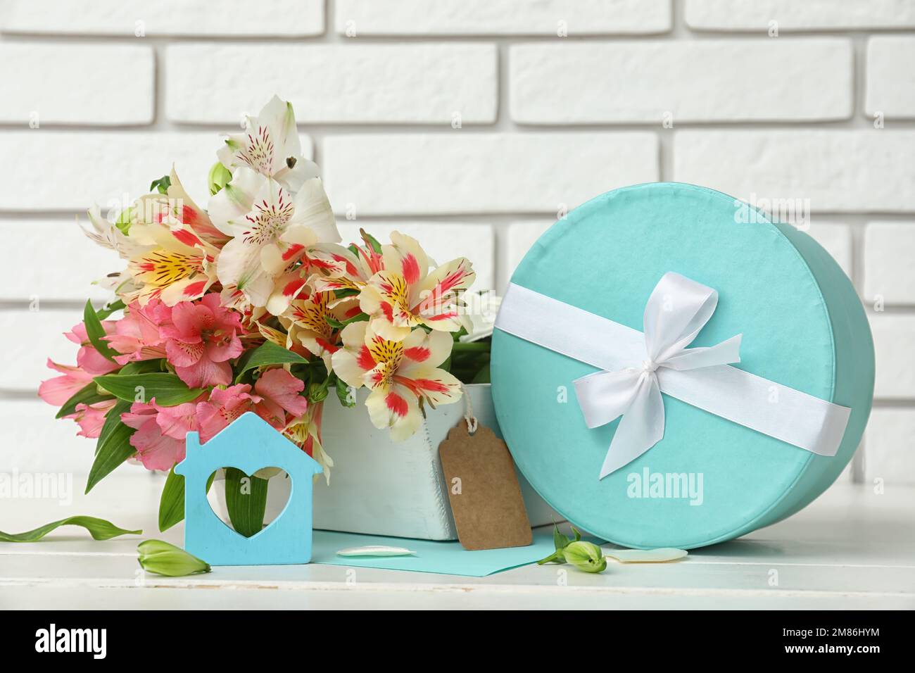 Beautiful alstroemeria flowers, gift box and decor on table near light ...