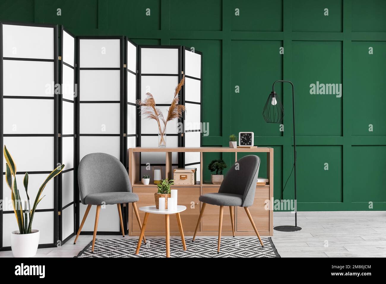 Interior of living room with folding screen, chairs and end table near ...