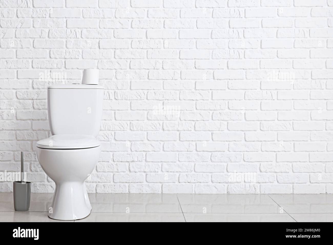 Modern toilet bowl near white brick wall Stock Photo - Alamy