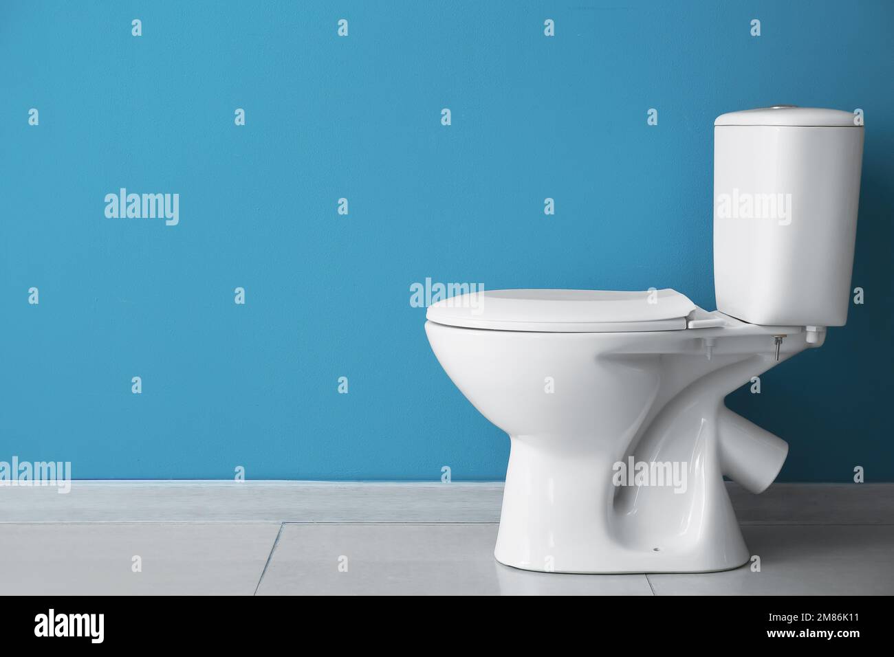 Ceramic toilet bowl near blue wall Stock Photo - Alamy