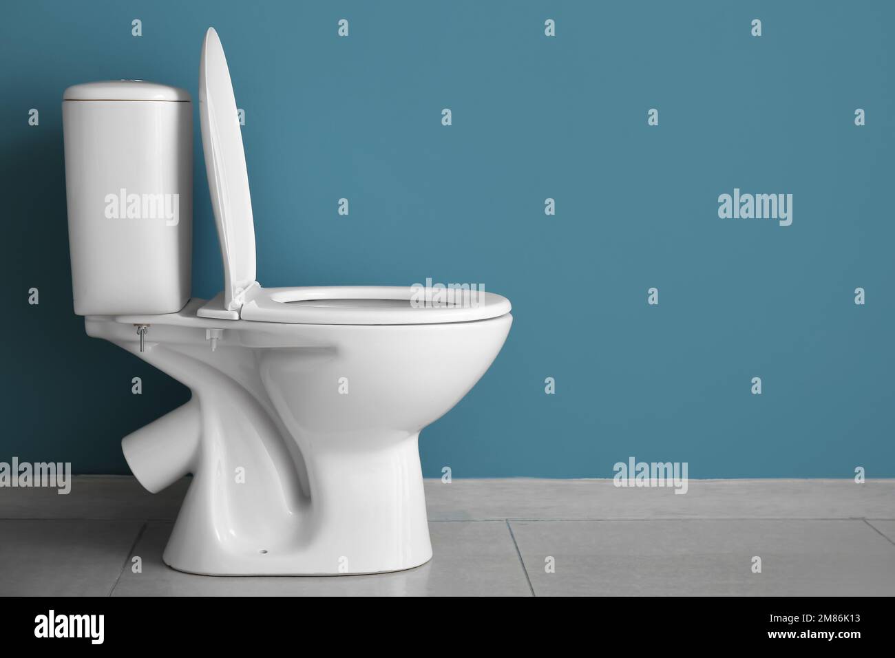 Ceramic toilet bowl near blue wall Stock Photo - Alamy