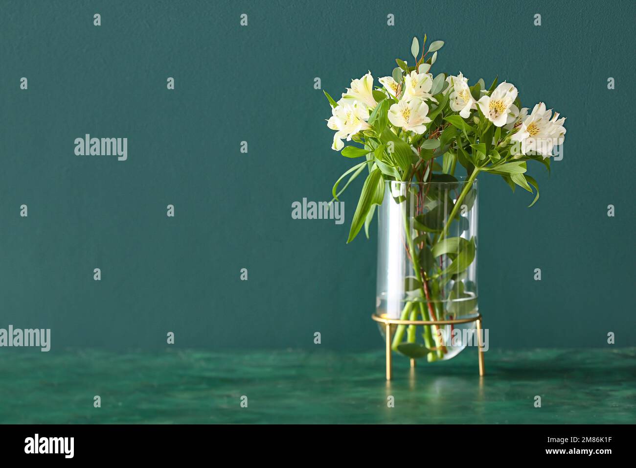 Glass vase with beautiful alstroemeria flowers on table near color wall ...