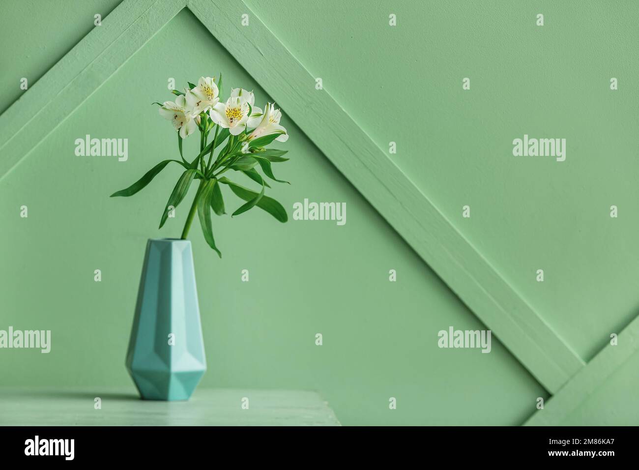 Vase with bouquet of alstroemeria flowers on green table near color ...
