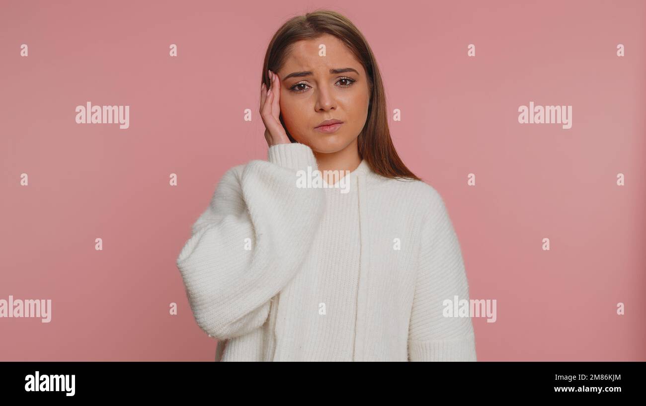 Hipster young adult woman in sweater rubbing temples to cure headache ...