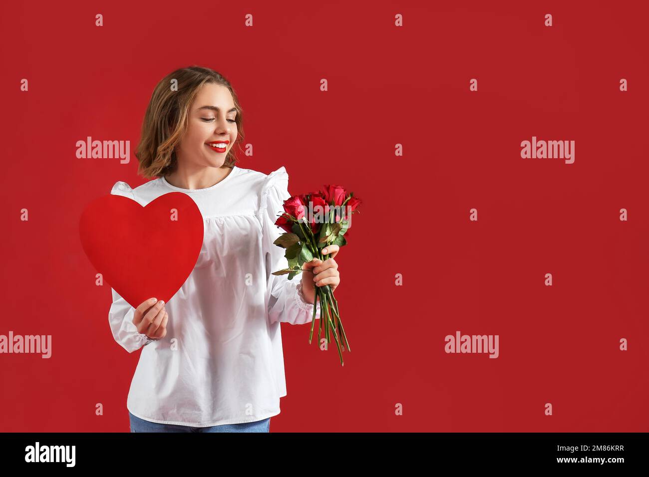 Beautiful young woman with paper heart and roses on red background ...