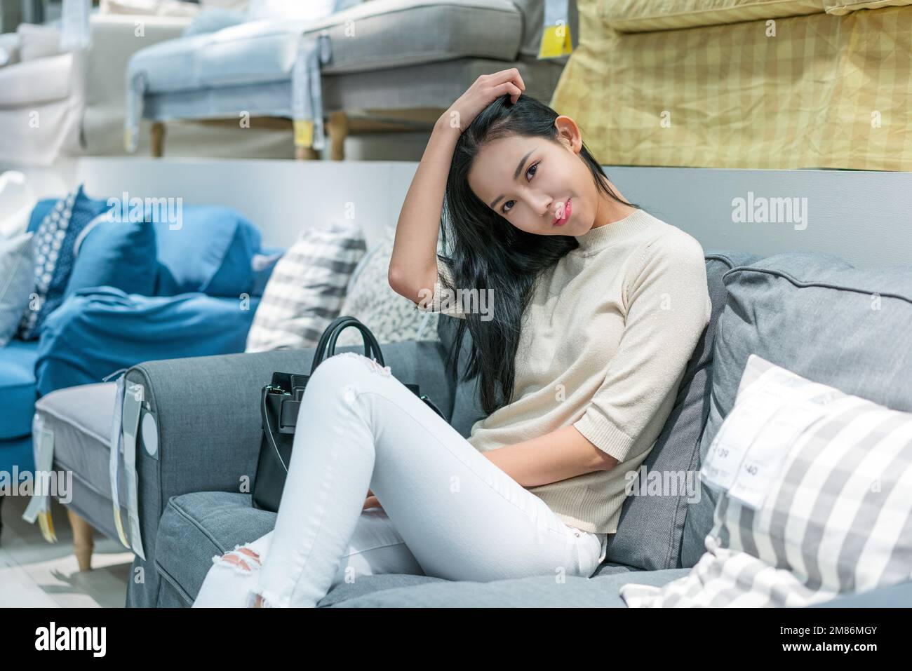 Young woman sitting on the sofa Stock Photo - Alamy