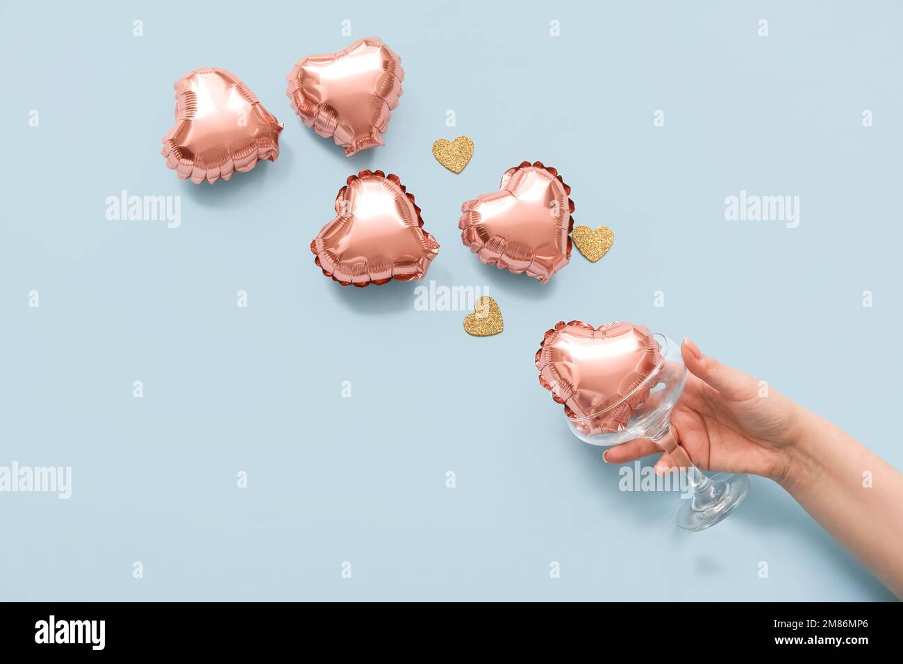 Female hand with glass, balloons and decor on color background ...