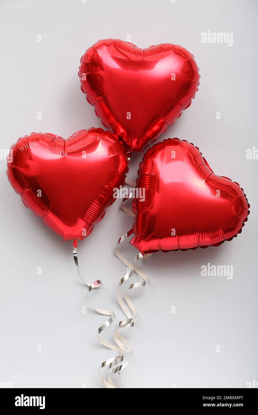 Red heart shaped balloons with ribbons on light background. Valentine's ...
