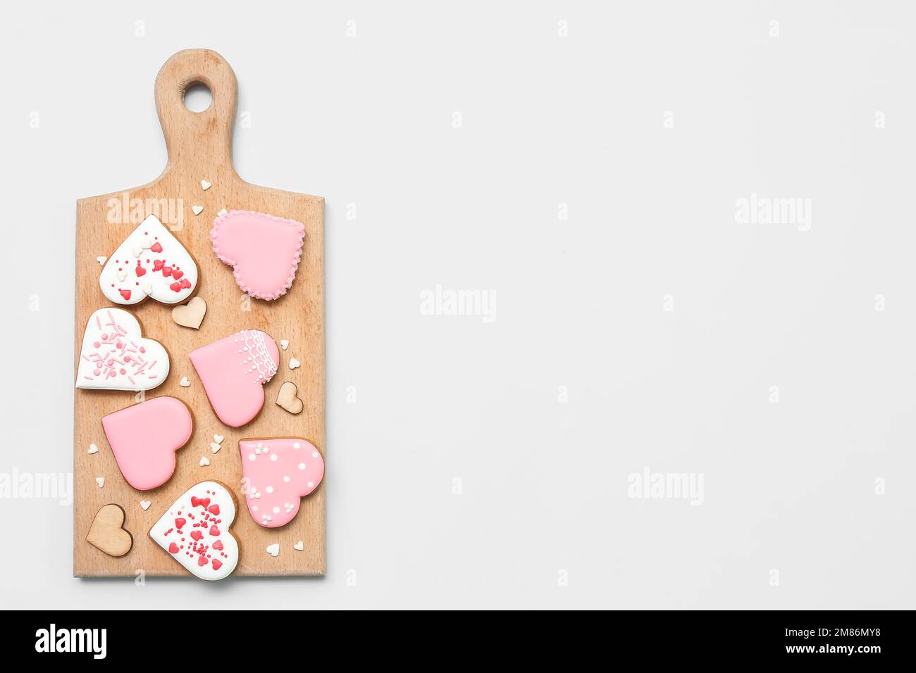 Wooden board with tasty heart shaped cookies on light background ...