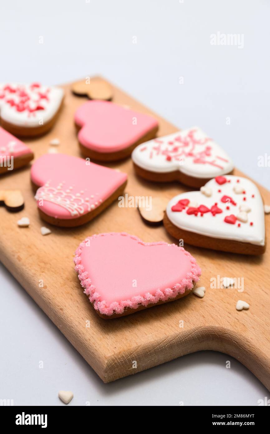 Wooden board with tasty heart shaped cookies on light background ...
