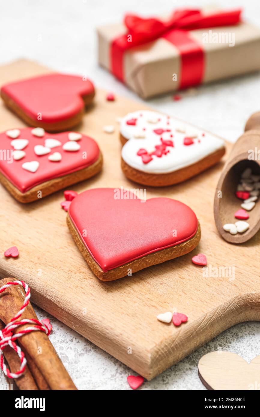 Wooden board with tasty heart shaped cookies on light background ...