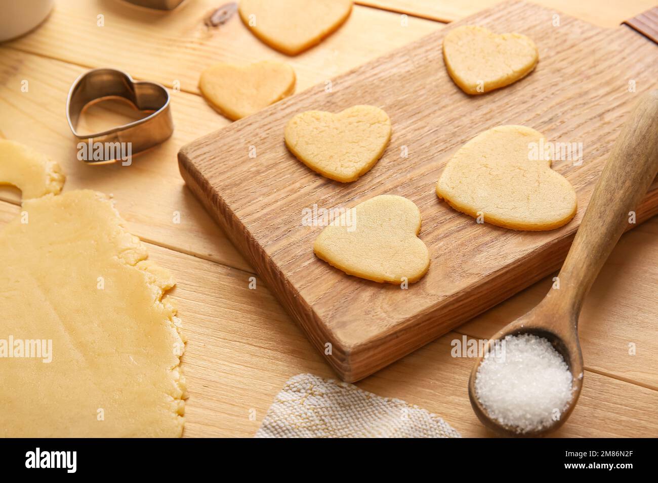 Board with raw heart shaped cookies on wooden table, closeup ...