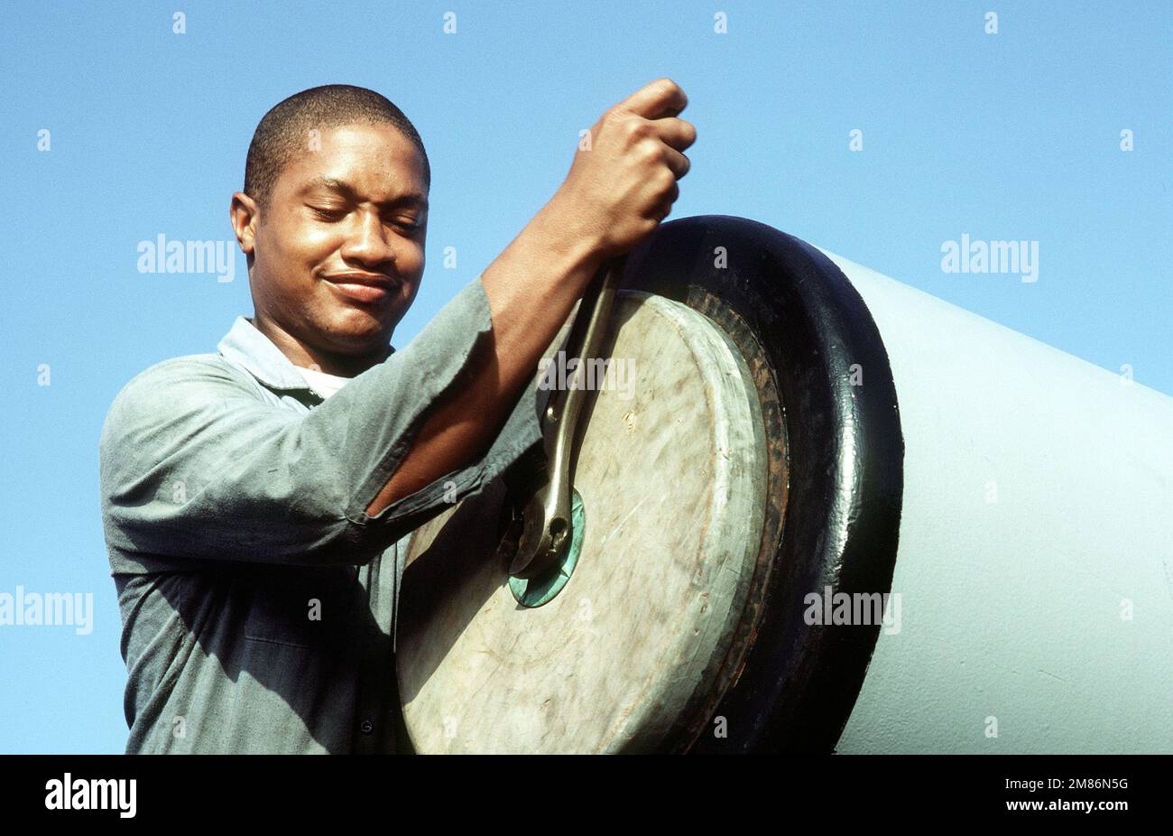 A crewman releases the plug on the muzzle of a Mark 7 16-inch/50 ...