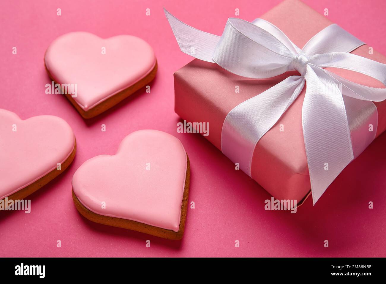 Beautiful gift box and heart shaped cookies on color background ...