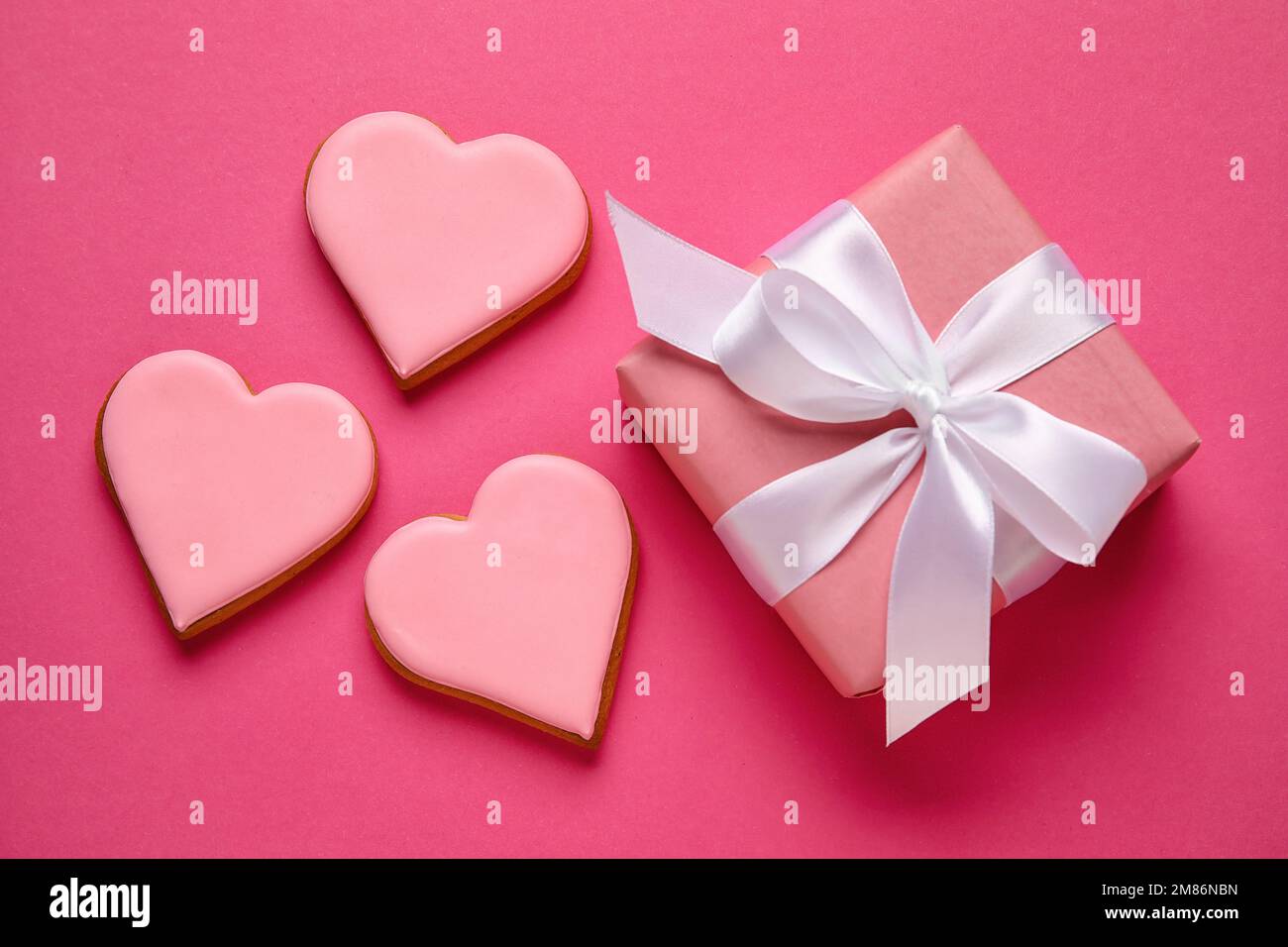 Beautiful gift box and heart shaped cookies on color background ...