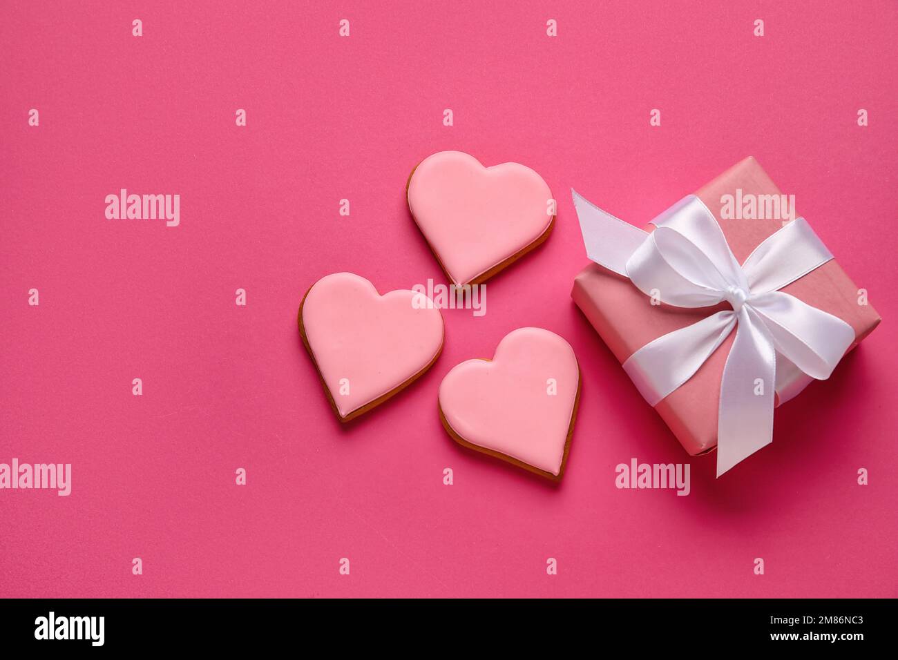 Beautiful gift box and heart shaped cookies on color background ...