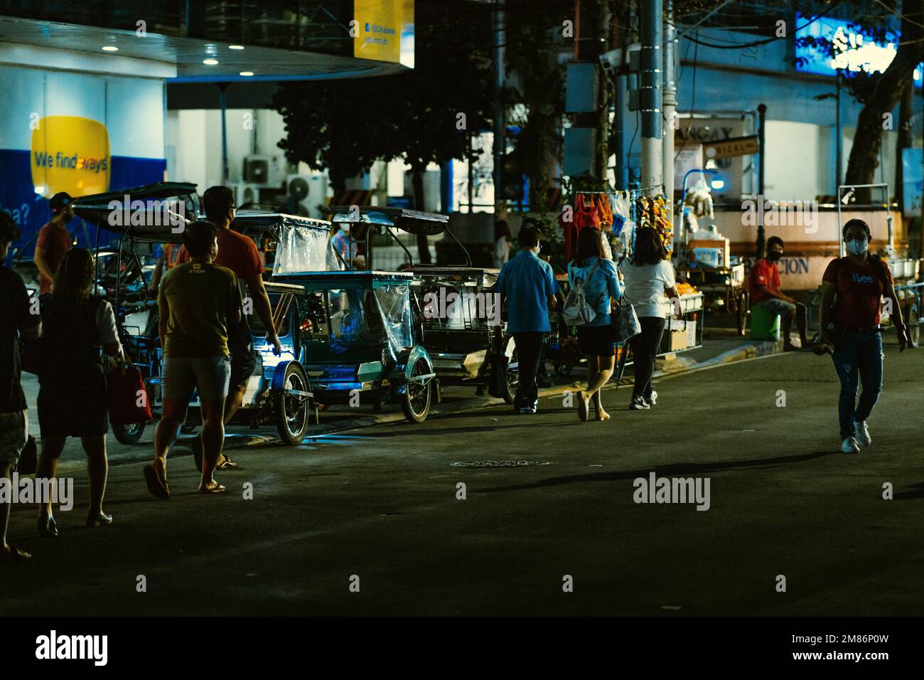 An empty street in the Philippines at night with people walking across ...