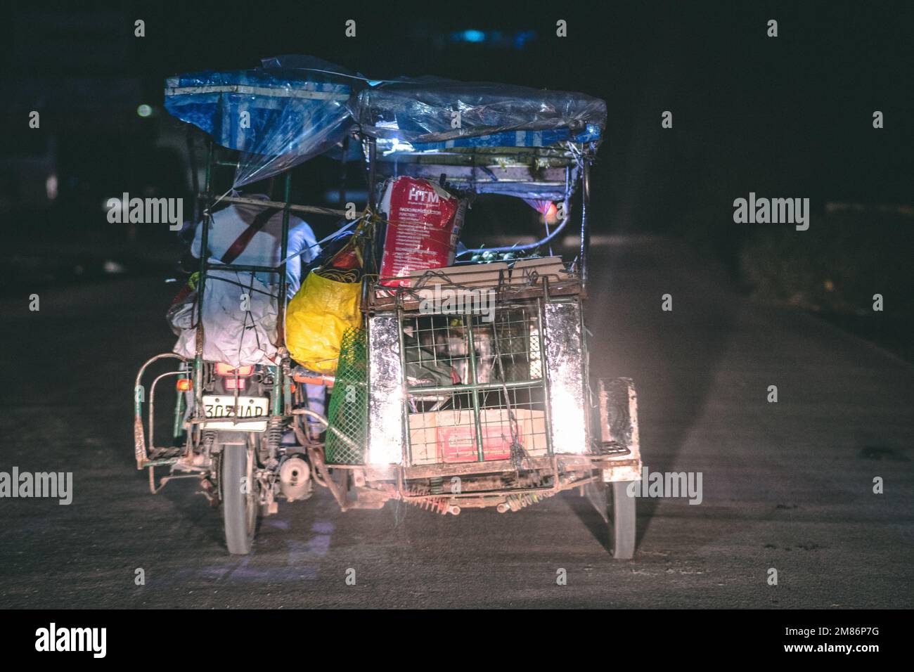 A car with a load of baggage on the back driving along an empty road at ...