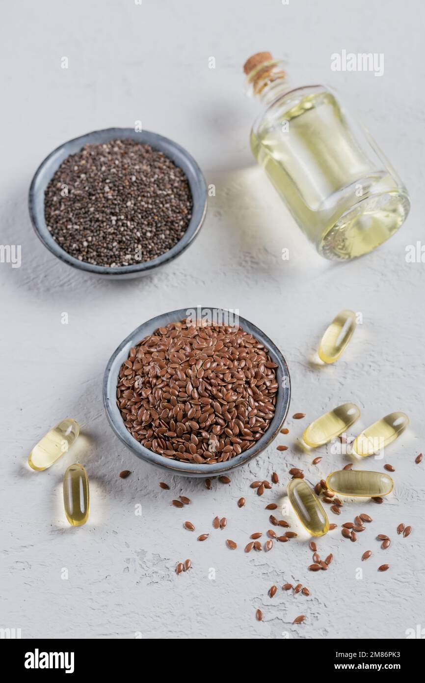 Brown flax seed or linseed and chia in small bowl and gelatin capsules ...