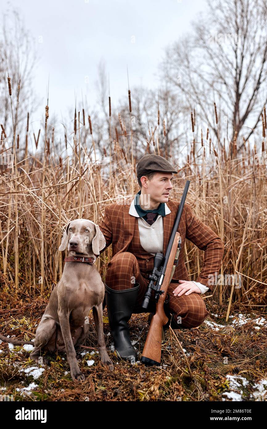 Serious caucasian hunter man with dog holding shotgun rifle walking in ...