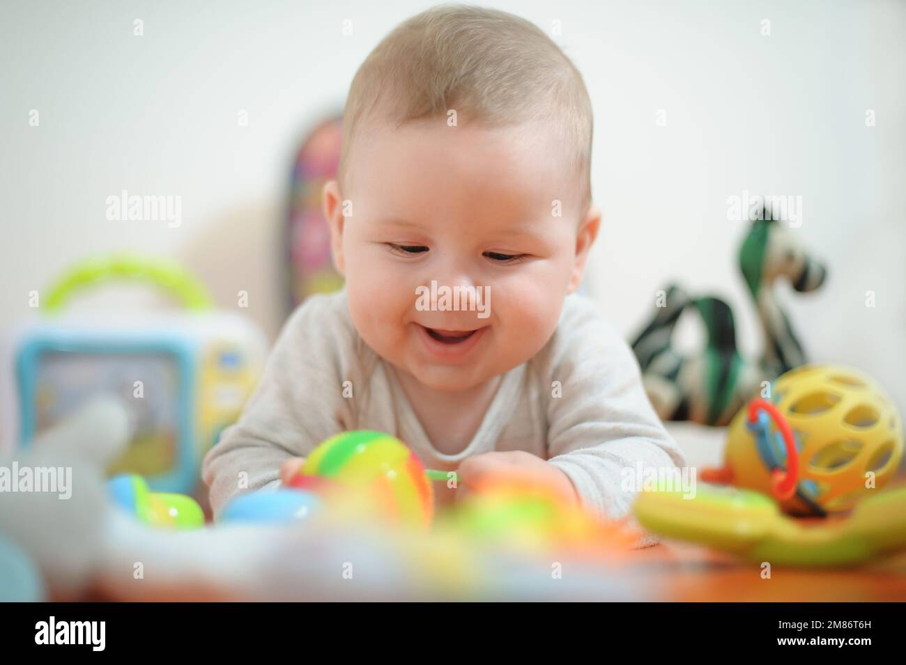 Baby plays with toys. Close-up view of cute baby boy lies on its ...