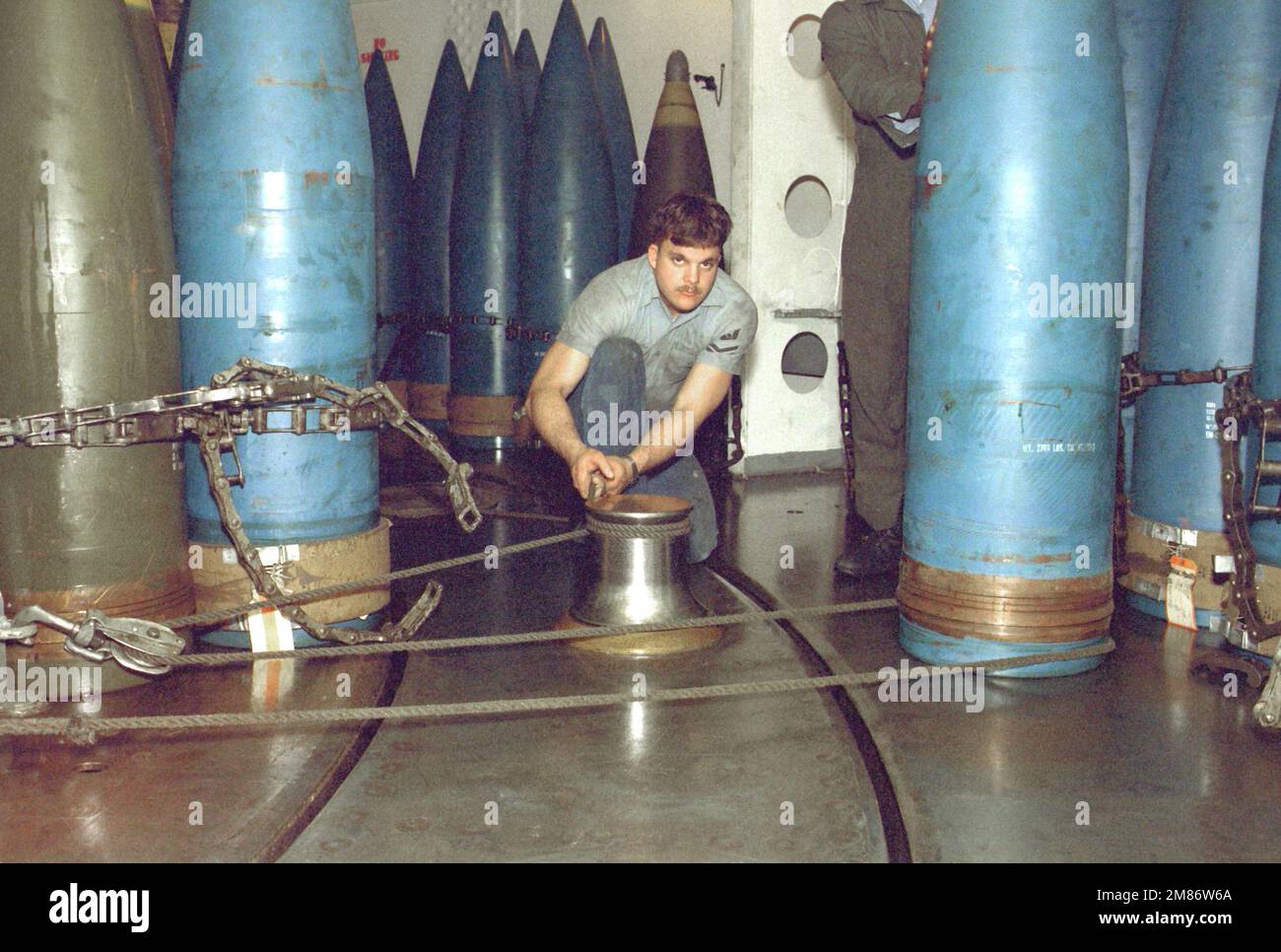 A petty officer tends a line as a 2,700-pound dummy projectile is drawn ...