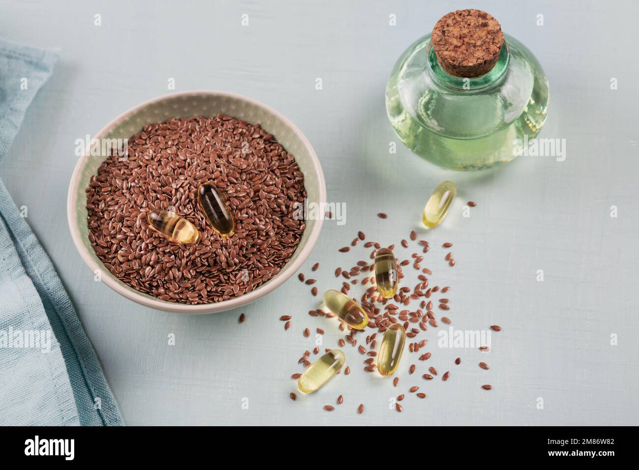 Brown flax seed or linseed in small bowl and gelatin capsules with ...
