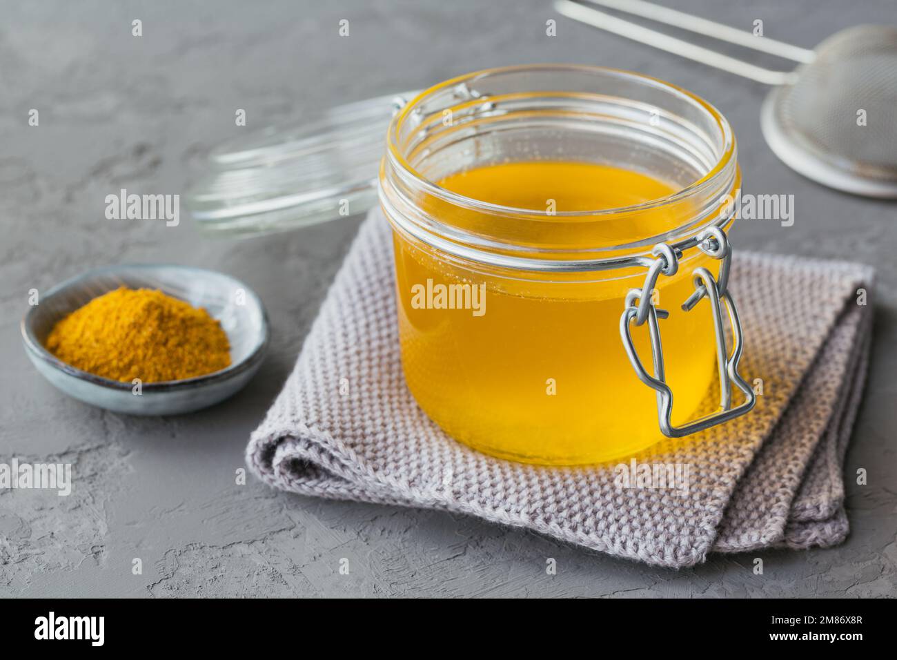 Homemade Ghee or clarified butter in a jar and turmeric powder on grey ...