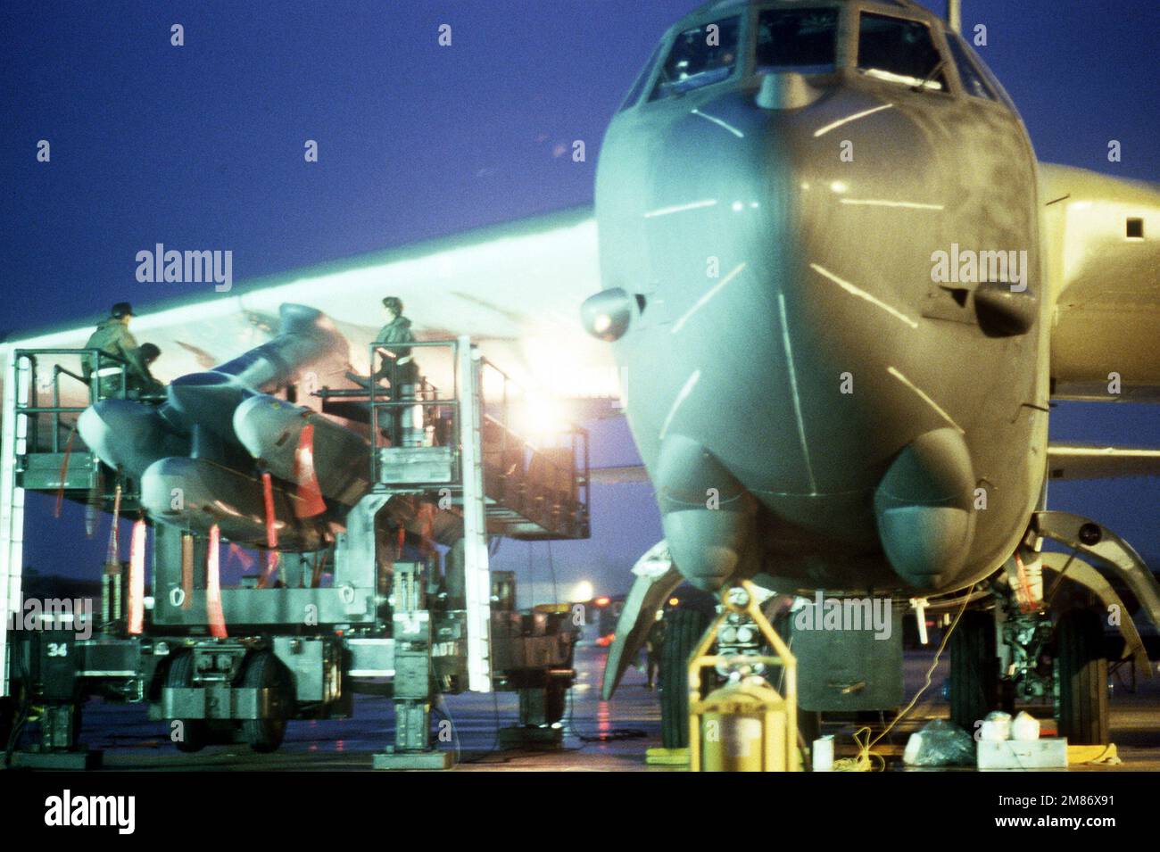 A munitions maintenance crew works at night to secure AGM-86B air ...