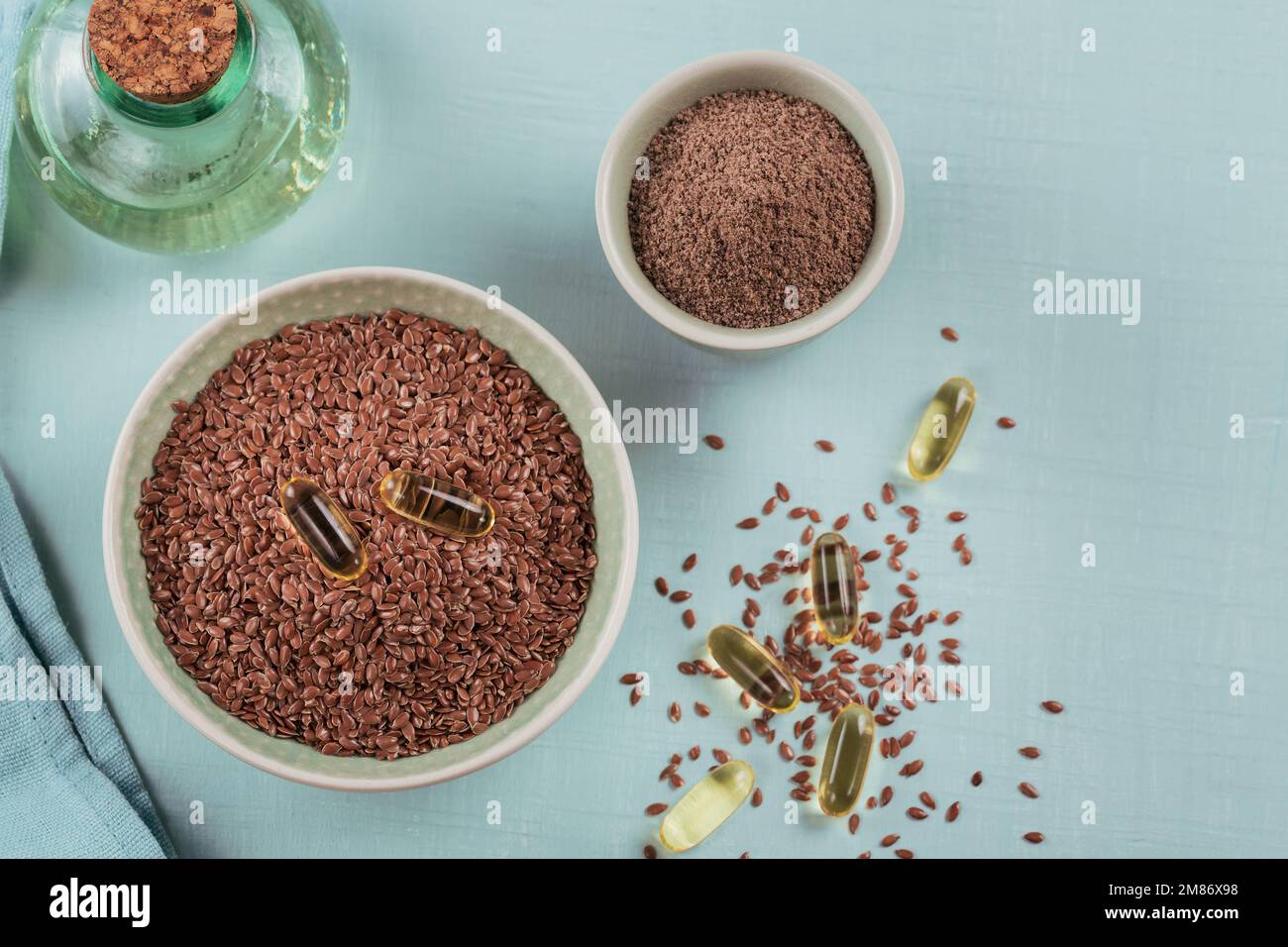 Brown flax seed or linseed and ground or crushed flaxseed in small bowl and gelatin capsules ...