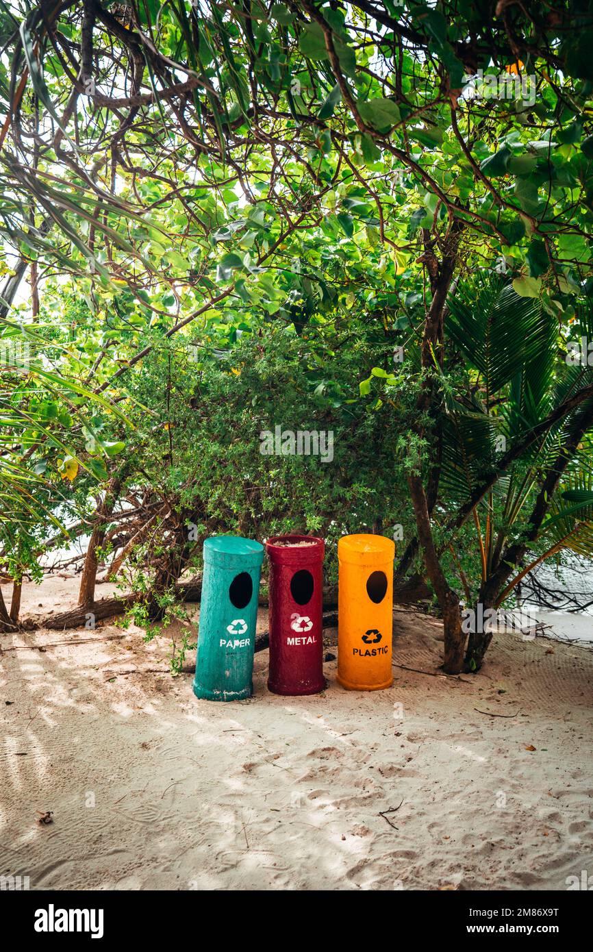 A vertical shot of three cylindrical recycling bins, plastic, metal ...