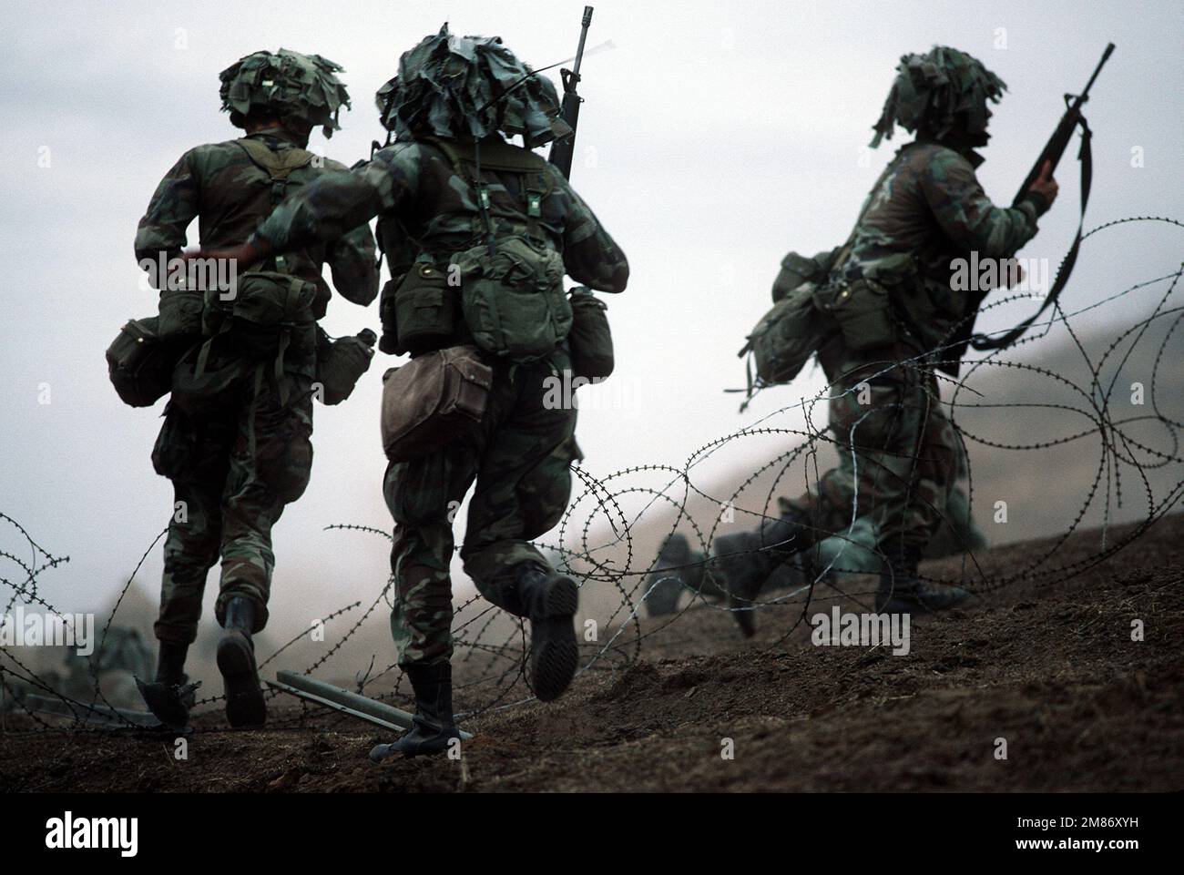 Soldiers of the 7th Infantry Division, armed with M-16A1 rifles, attack ...