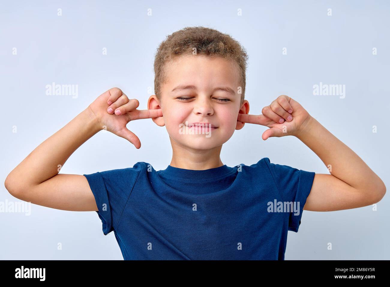 little child boy closing eyes and discontentedly closing ears with ...