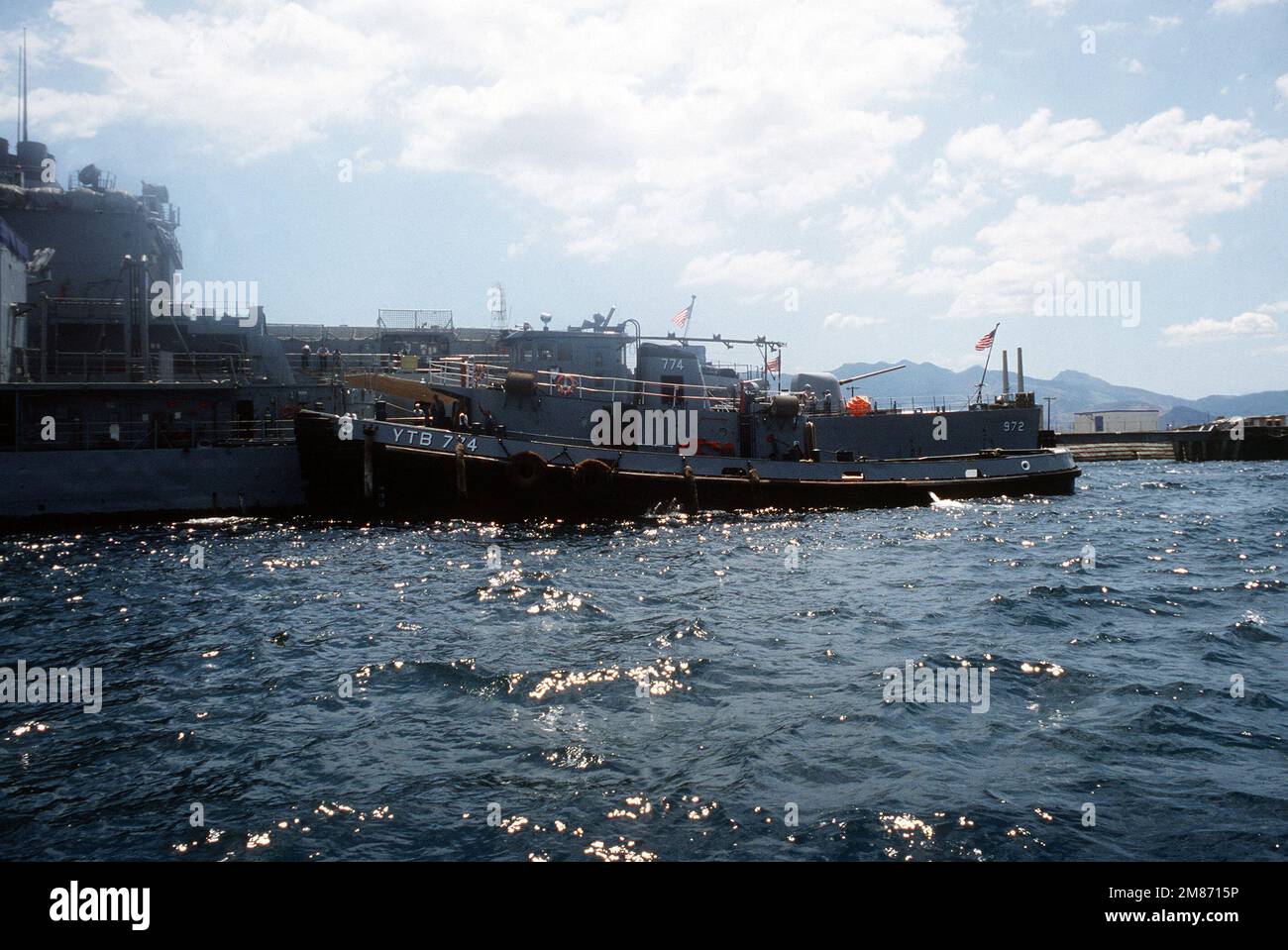 The large harbor tug NASHUA (YTB-774) assists in positioning an ...