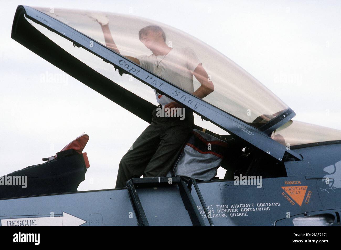 A USAF crew chief cleans the canopy of an F-16 Falcon fighter aircraft ...