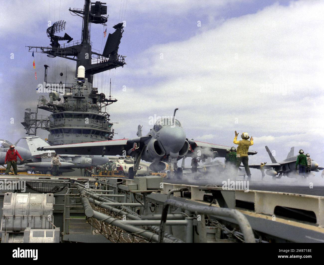 A flight deck crew member signals to the pilot of an A-6E Intruder ...