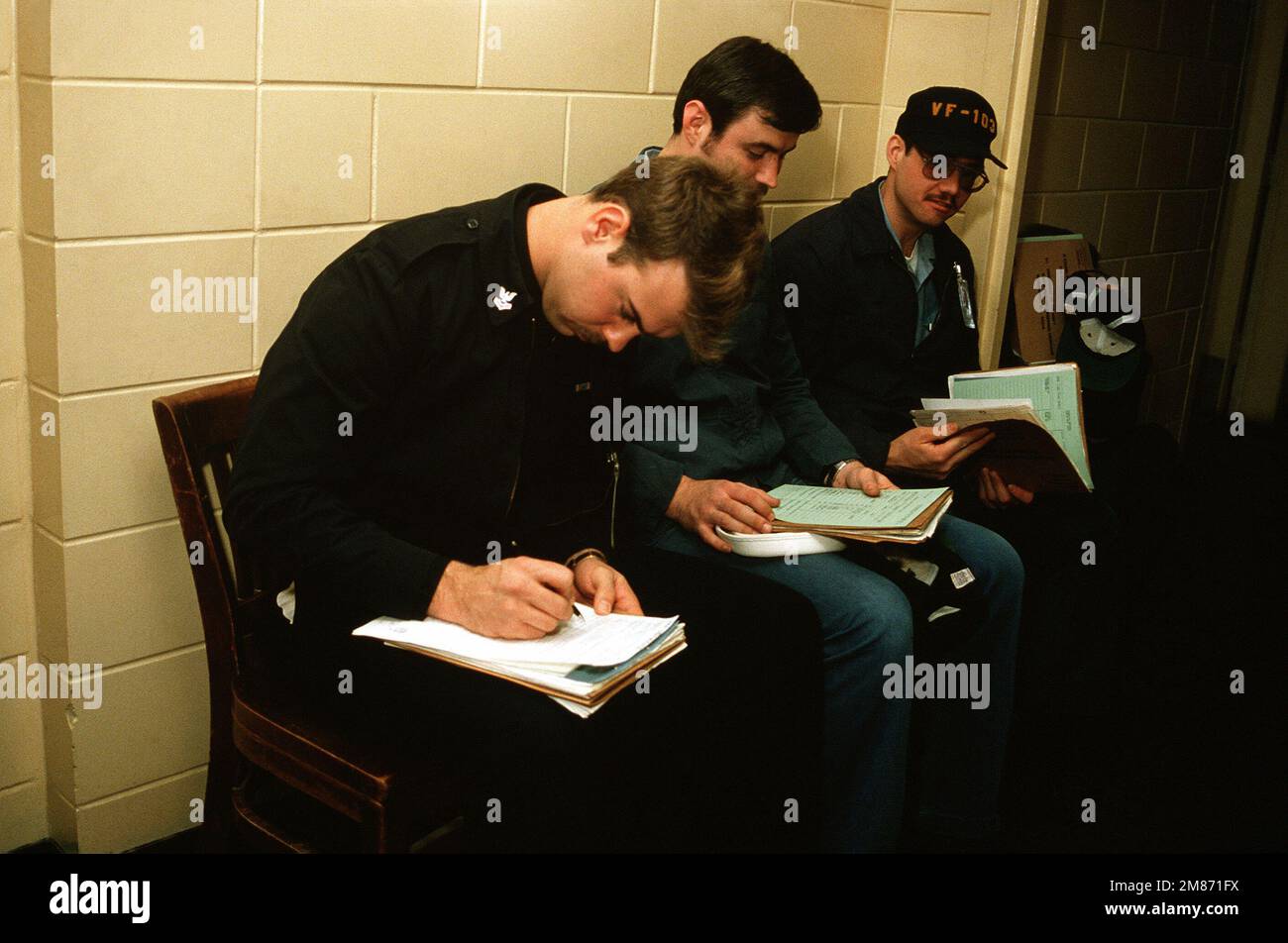 Sailors fill out paperwork and look over their service record books as ...