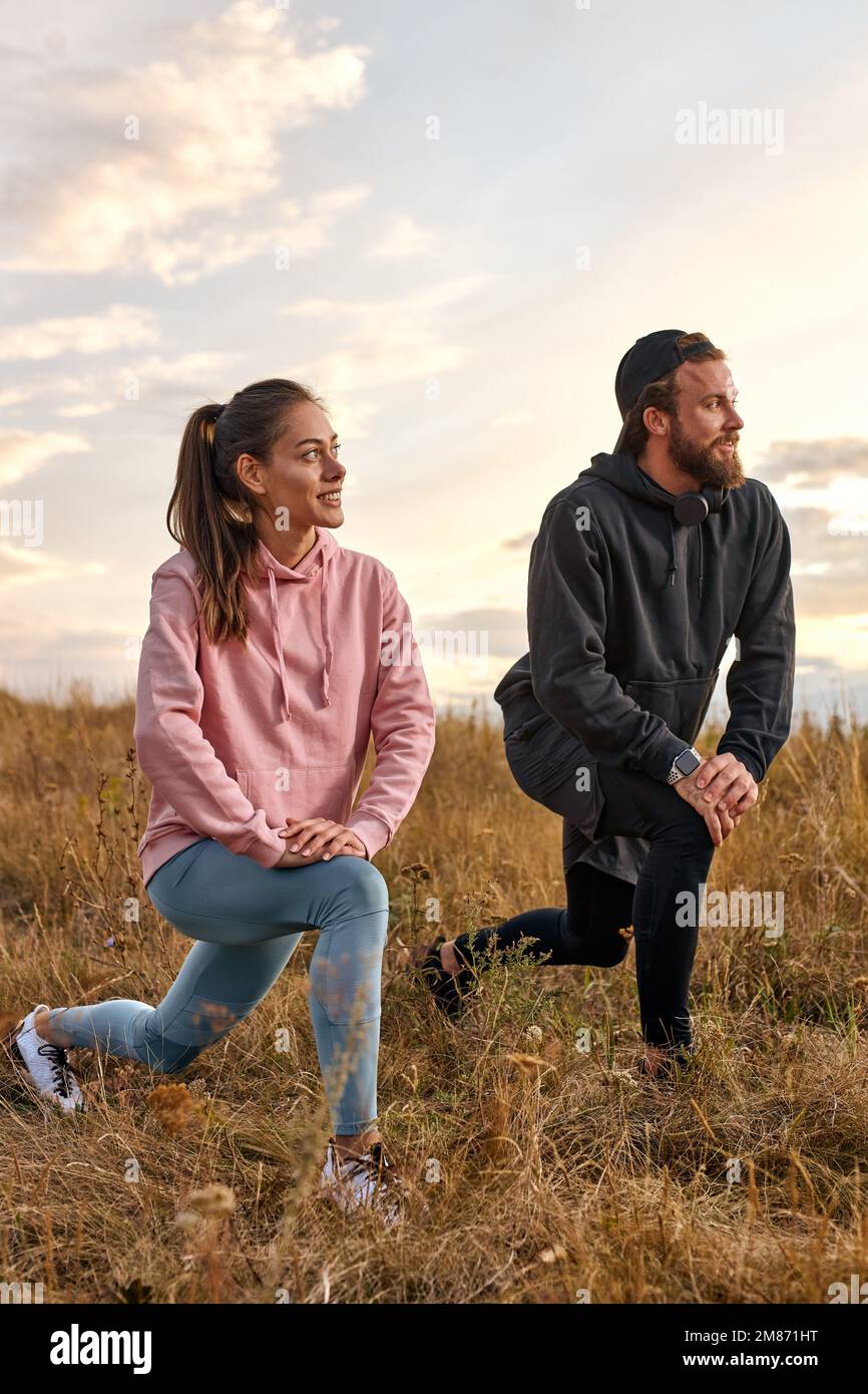 athlete couple warming up before running, stertching legs with ...
