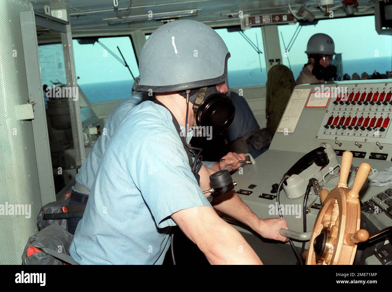 A crew member wearing nuclear-chemical-biological warfare gear mans the ...