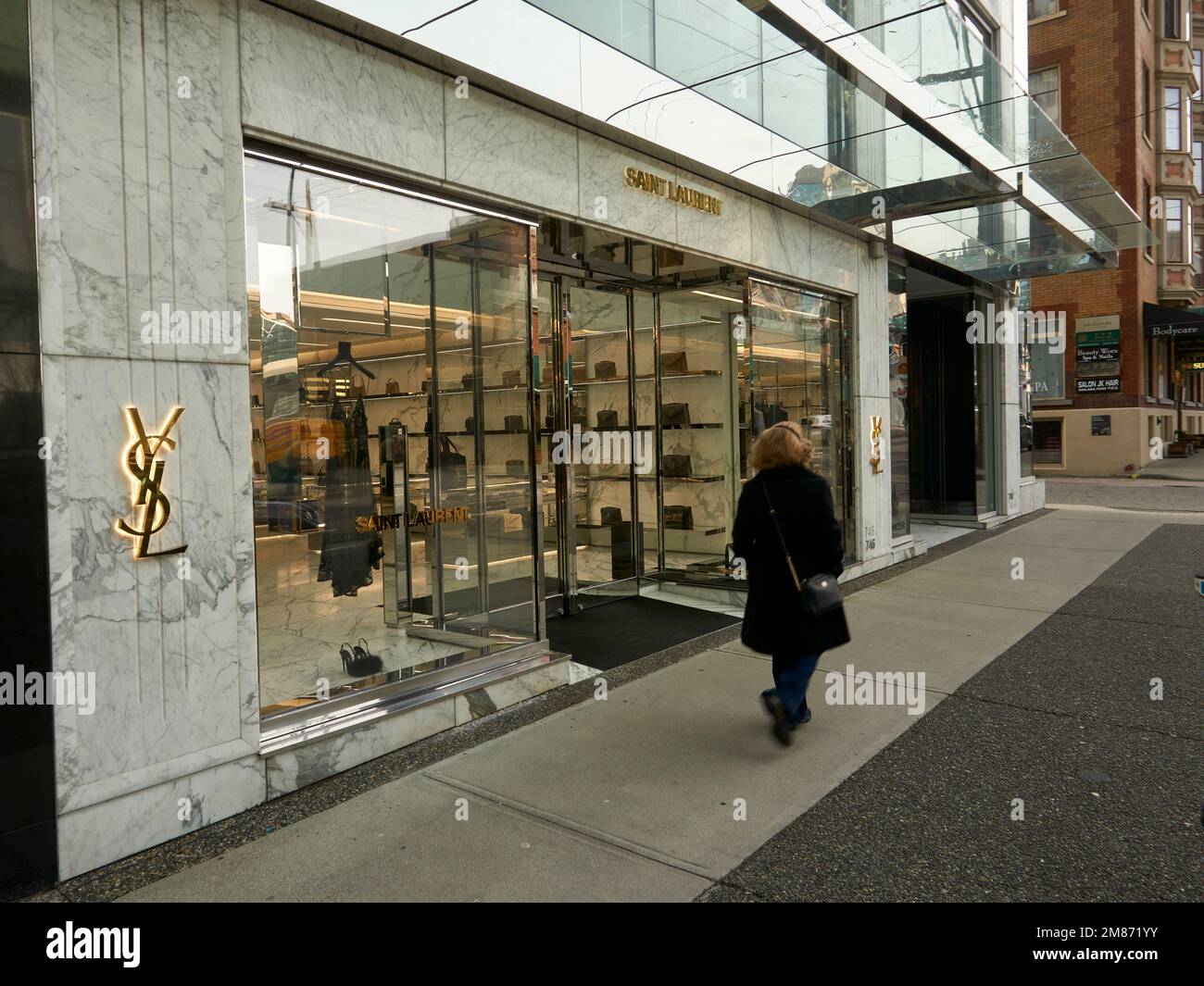 Woman walking past an Yves Saint Laurent store in downtown Vancouver ...