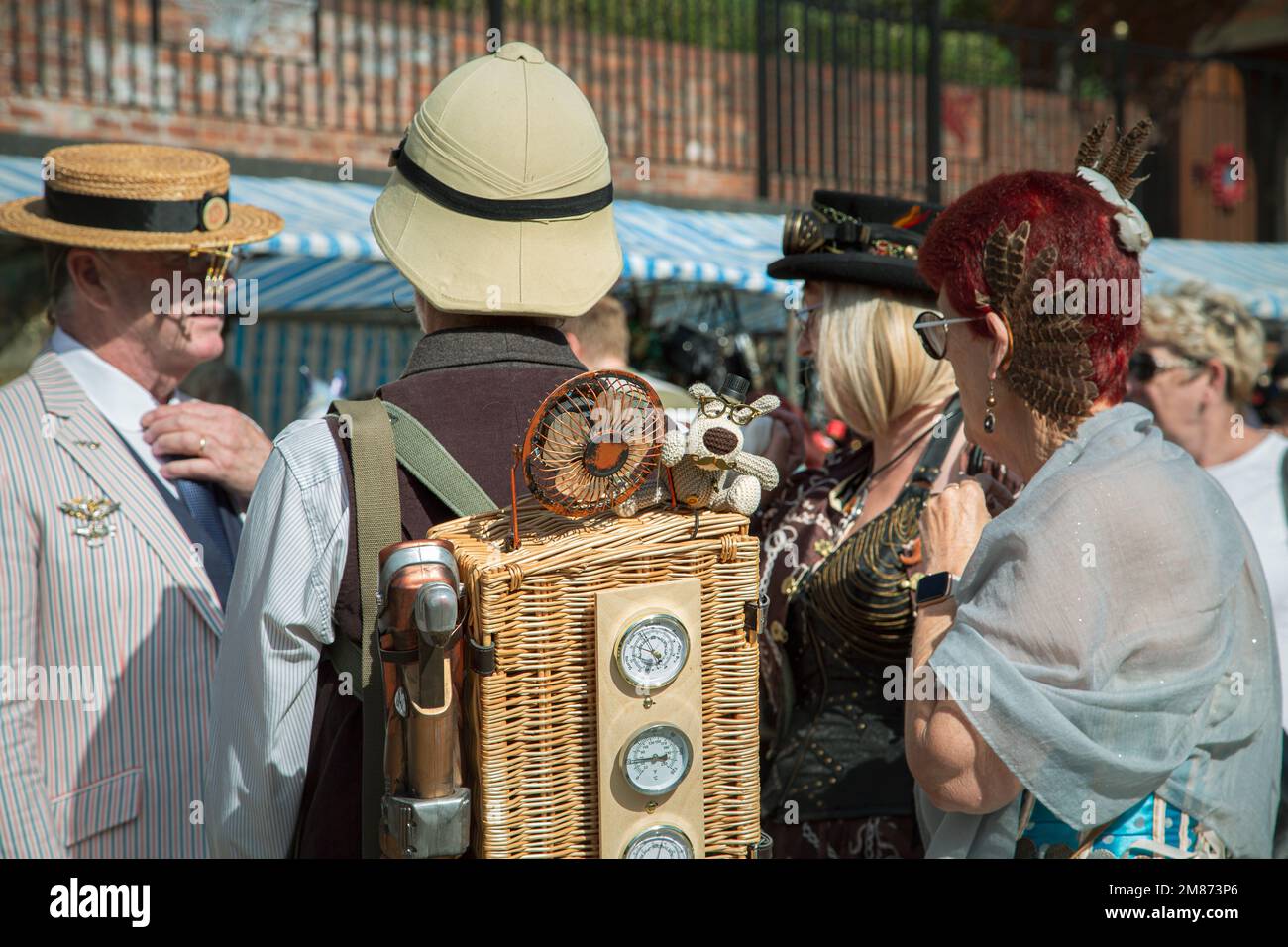 A group of people at a steampunk festival. A man in a pith helmet has a ...