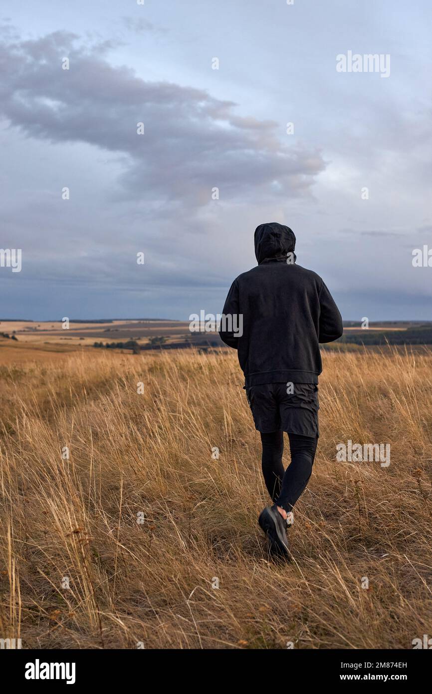 fit man running at sunset or sunrise along field mountains, morning ...