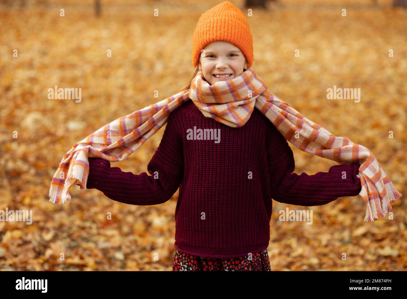 Cheerful, merry, delightful, smiling little blond girl put on plaid ...