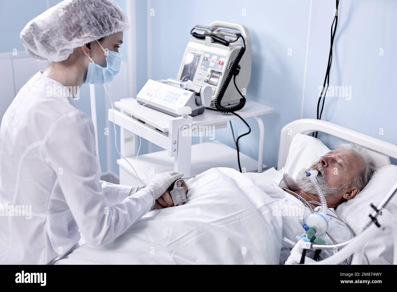 Young Female Doctor Treating Sick Aged Person Lying On Medical Bed With ...