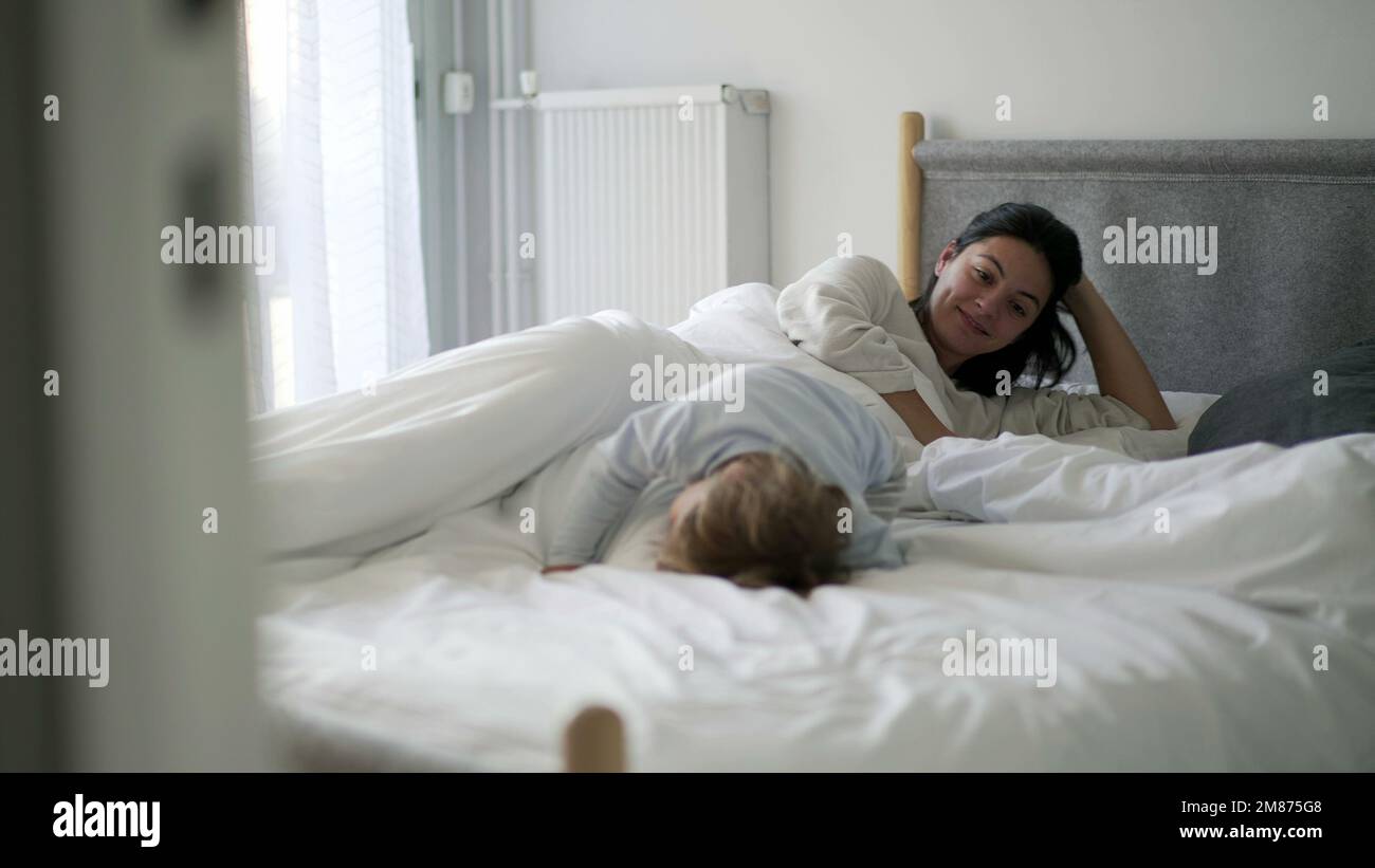Candid cute baby toddler in bed in the morning bouncing and falling ...