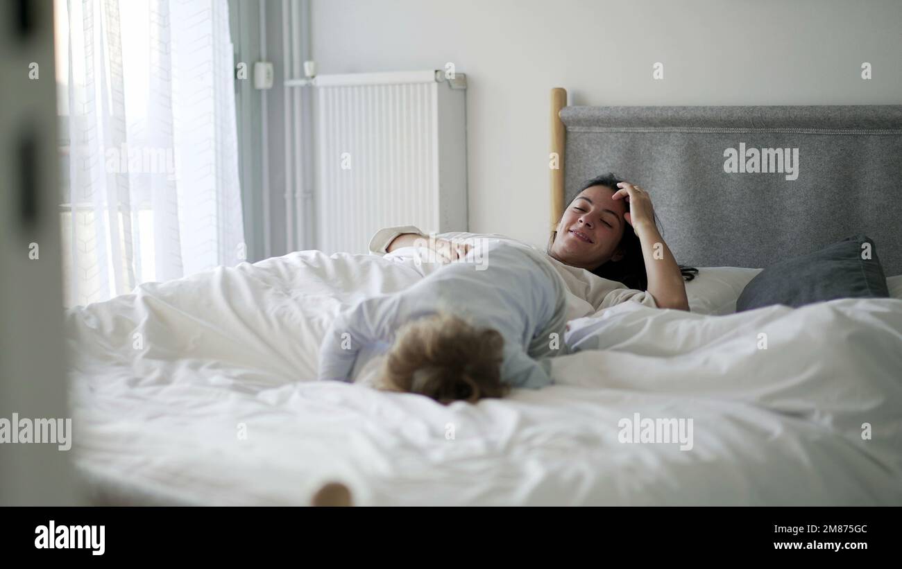Candid cute baby toddler in bed in the morning bouncing and falling ...